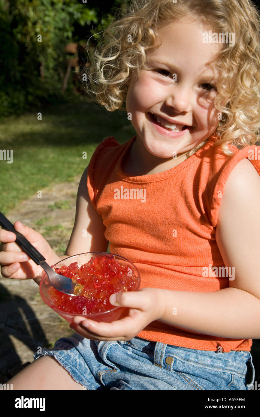 Young girl sitting in a backyard eating jello Stock Photo - Alamy