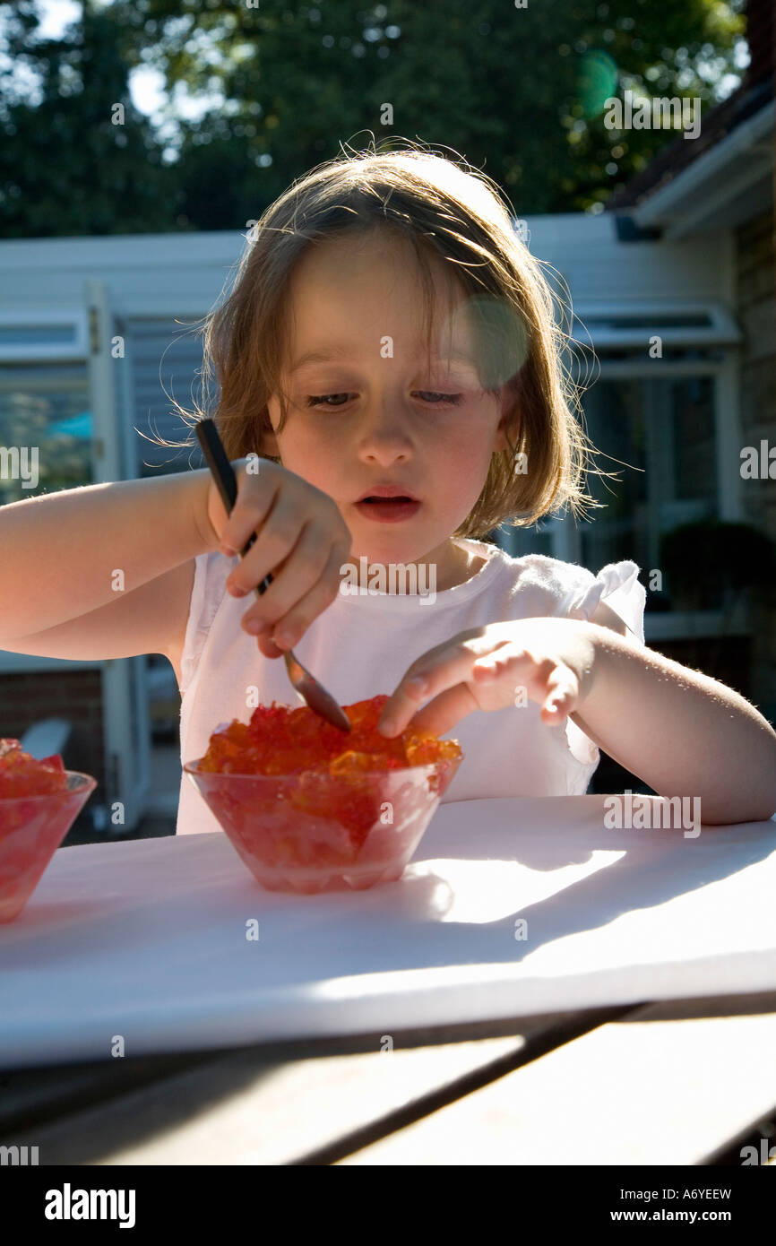 Young girl eating jello at a table in a backyard Stock Photo - Alamy
