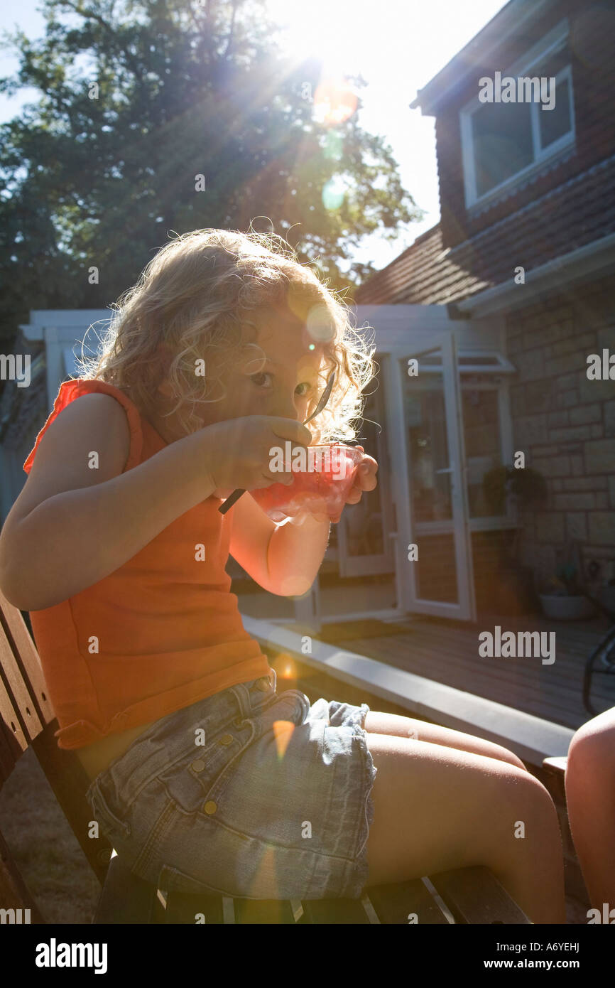 Young girl sitting on a chair in a backyard eating jello Stock Photo ...