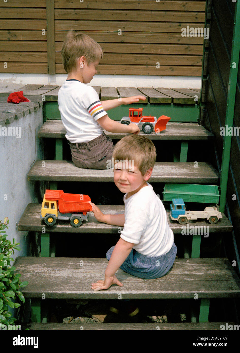 Two young boys playing with toys on steps Stock Photo - Alamy