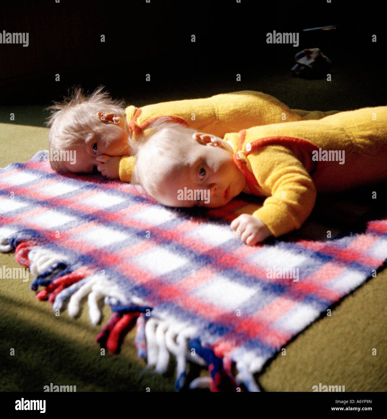 Two babies lying on rug Stock Photo - Alamy