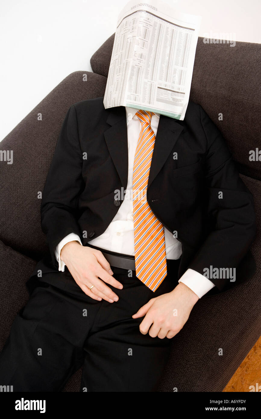 Businessman lying down on a sofa with a newspaper over his head Stock ...