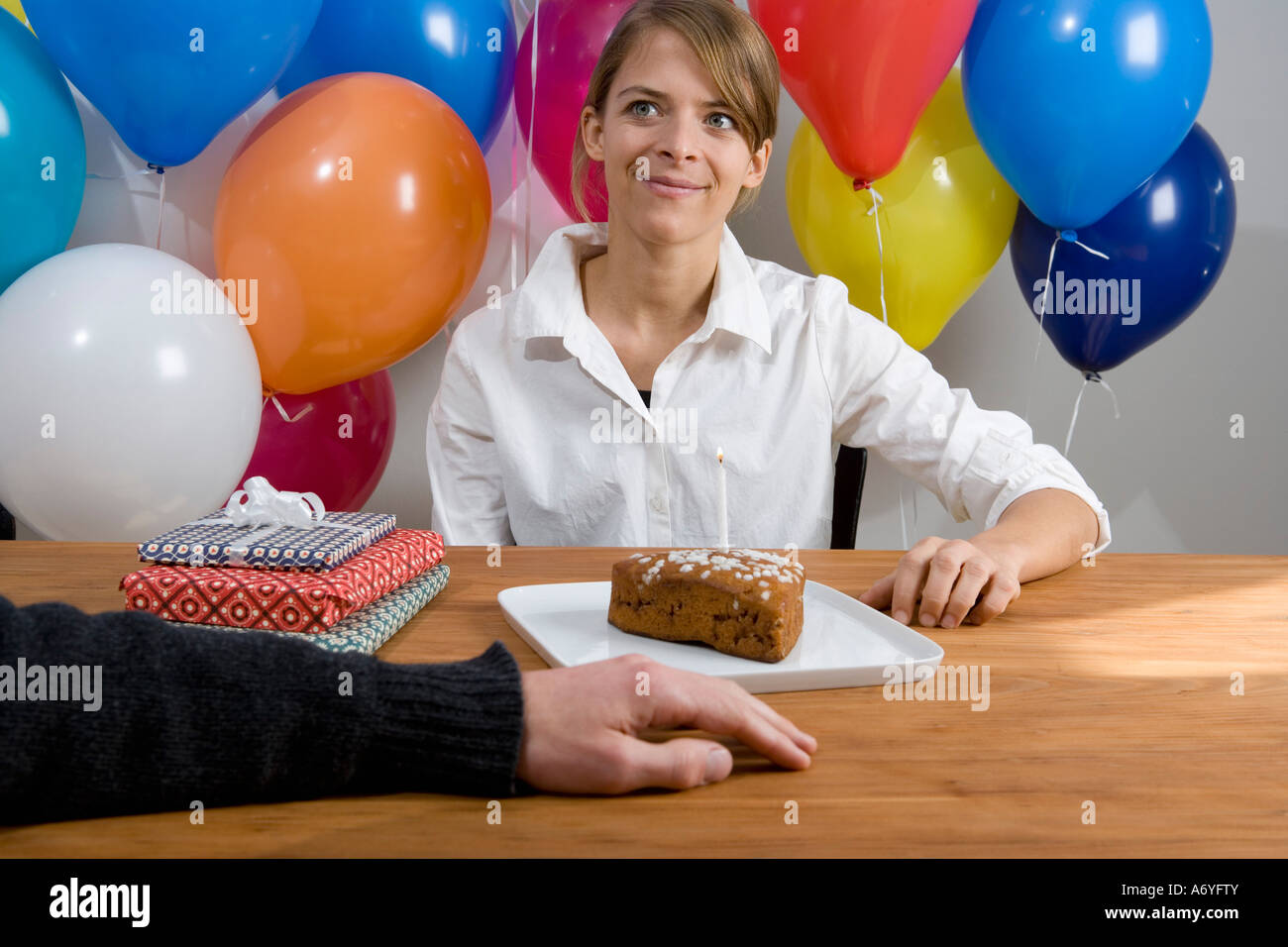 Couple sitting at table with birthday cake and balloons Stock Photo - Alamy