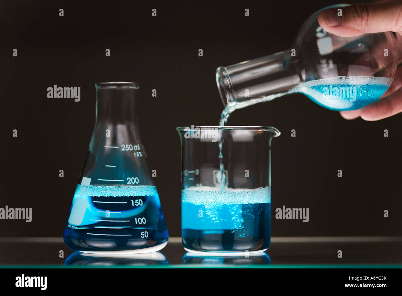 Close up of a man pouring blue liquid into a beaker Stock Photo - Alamy