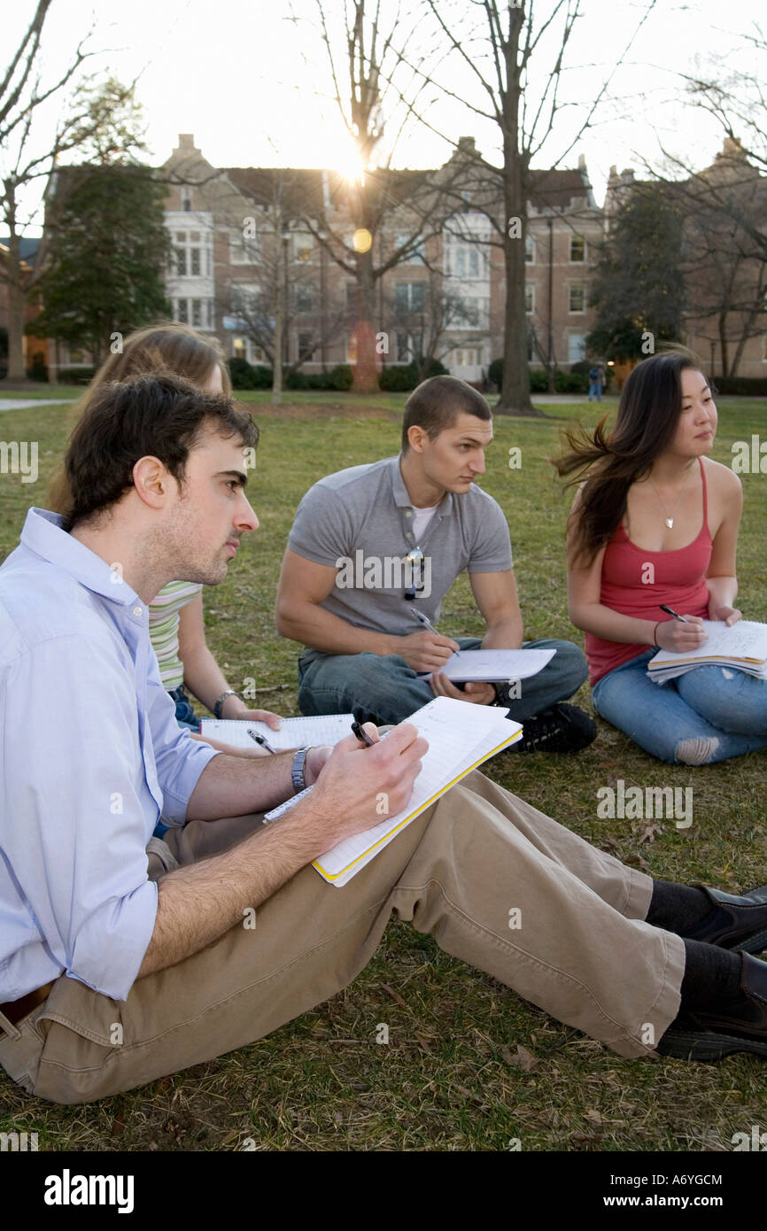 University students sitting on grass writing Stock Photo - Alamy