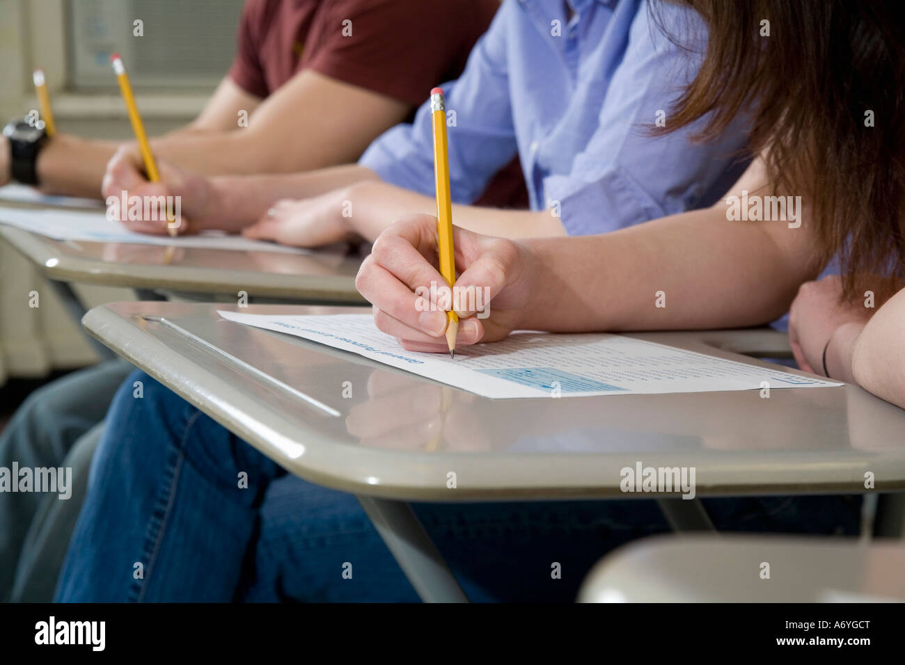 Students sitting at desks and writing Stock Photo - Alamy