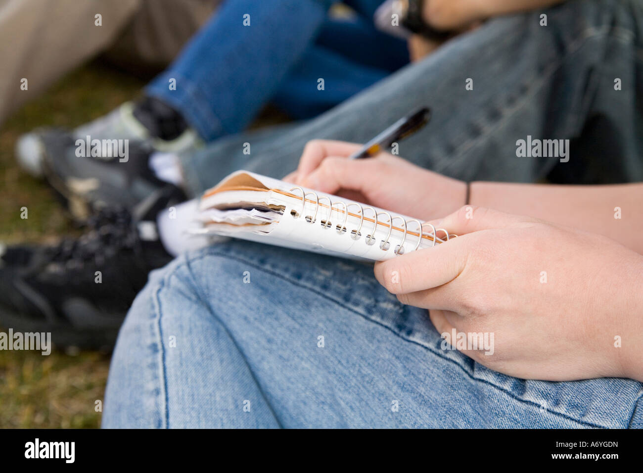 Students sitting on grass writing Stock Photo - Alamy