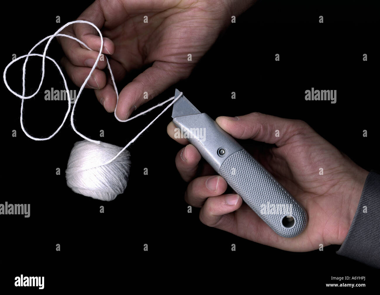 Man cutting string with a utility knife Stock Photo - Alamy