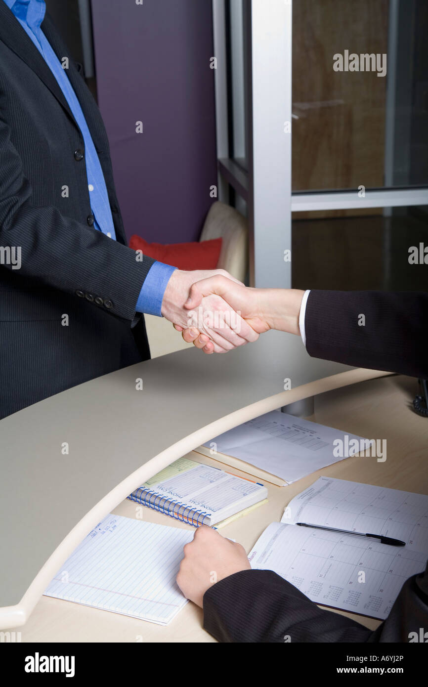 Two men shaking hands over a desk Stock Photo - Alamy
