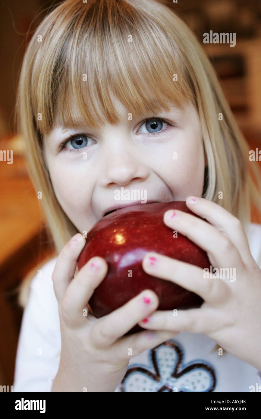 A young girl eating a red apple Stock Photo - Alamy