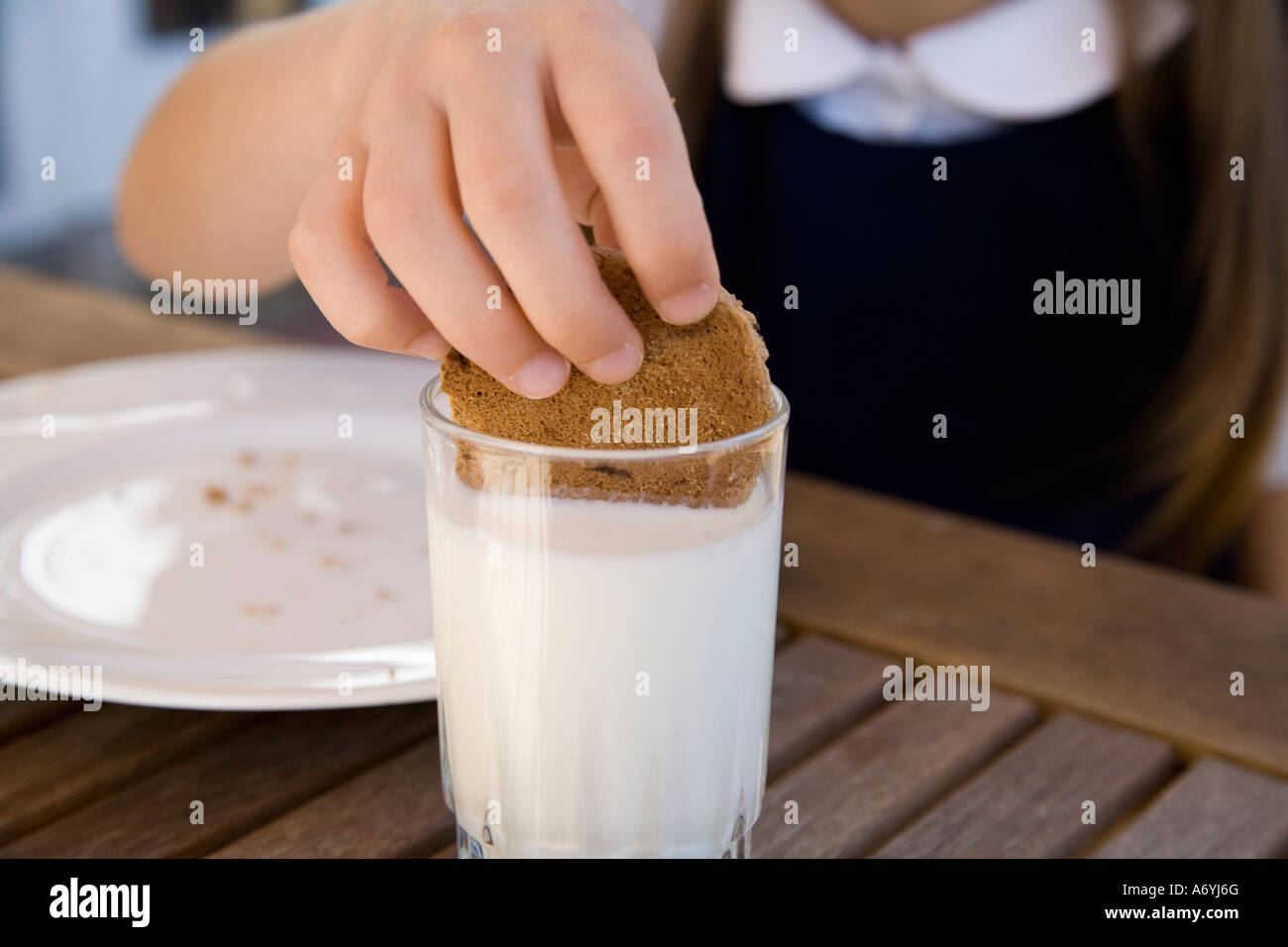Child dipping a biscuit into a glass of milk Stock Photo - Alamy