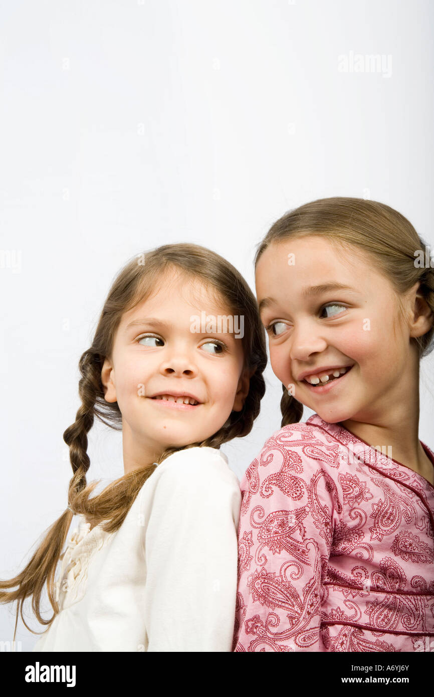 Two girls sitting back to back Stock Photo - Alamy