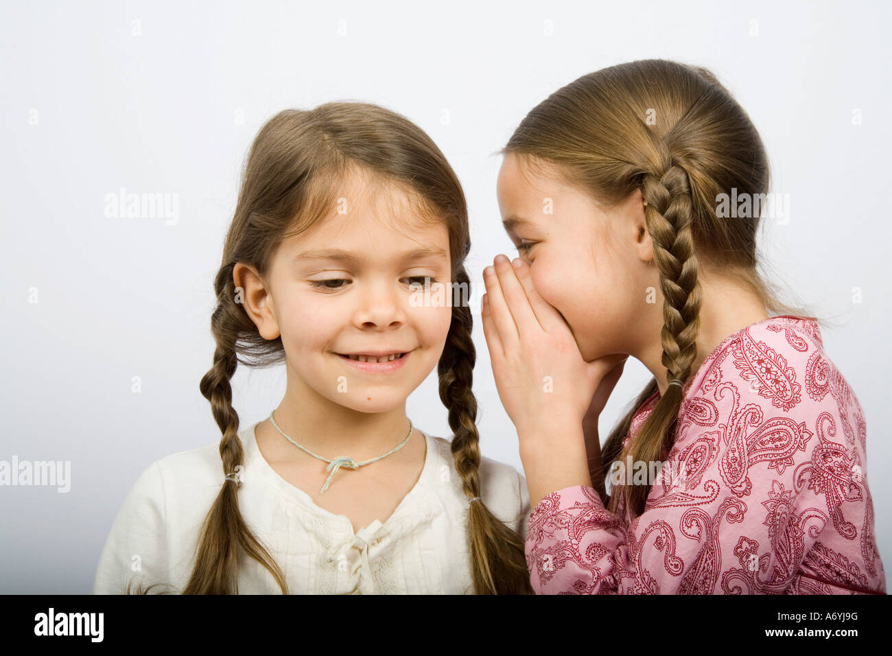 Two young girls whispering Stock Photo - Alamy