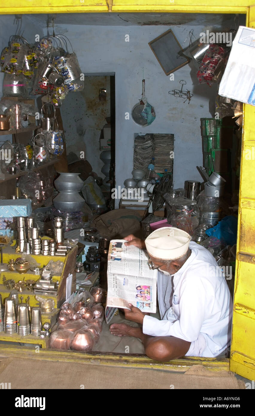 Merchant of brass and bowls sits in his shop reading the newspaper ...