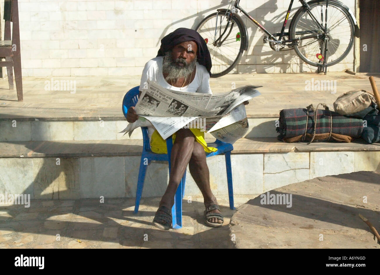 Native, Indian man reading a newspaper in the sunshine of Pushkhar ...