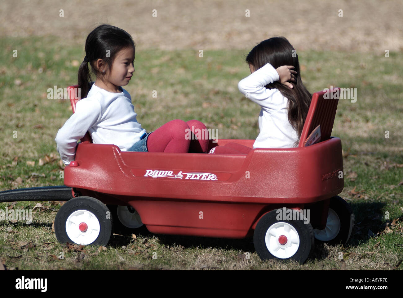 Two young girls sitting in a wagon Stock Photo - Alamy