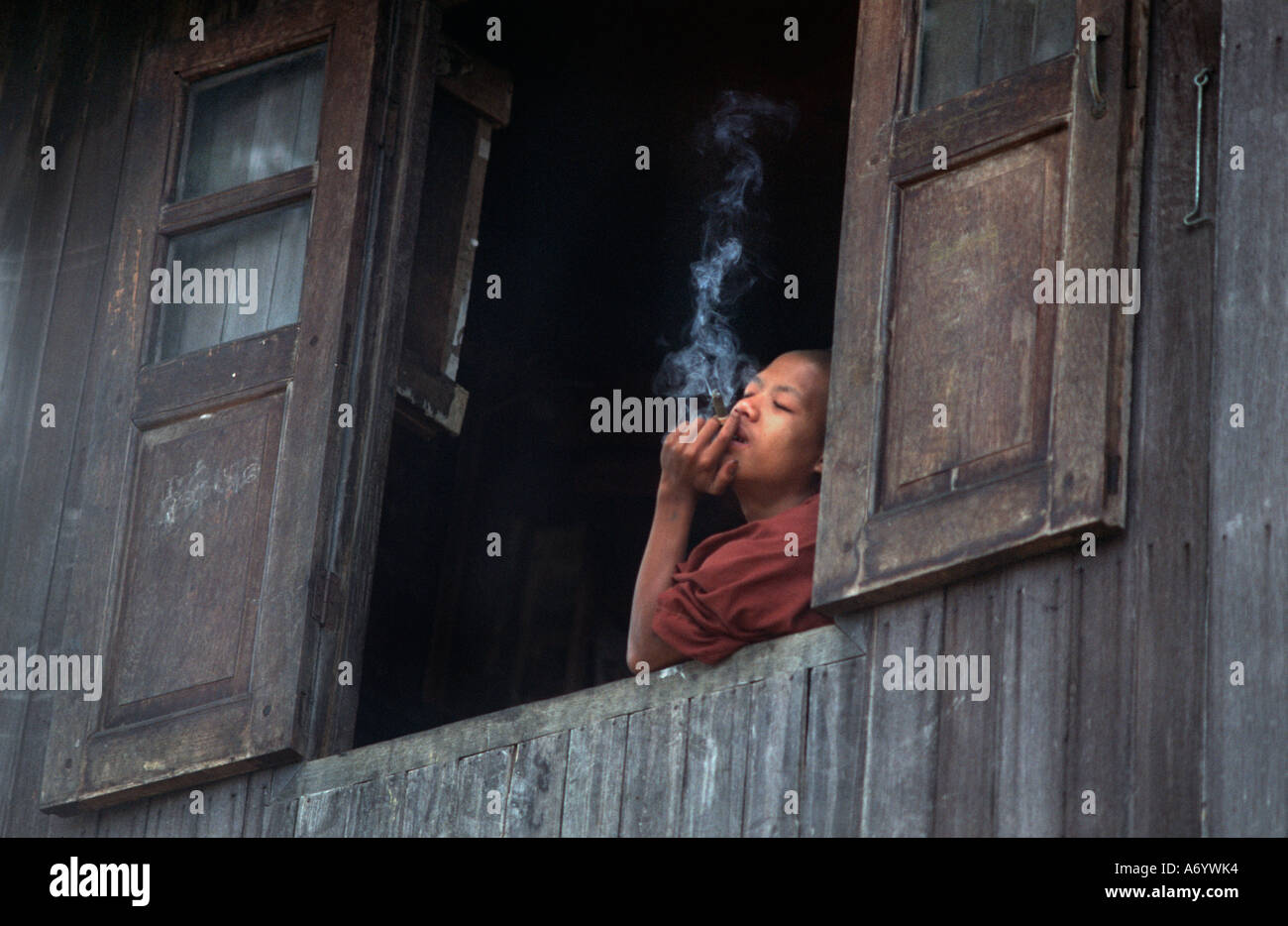 Monk smoking from the window of his quarters Shwe Min Bone village ...