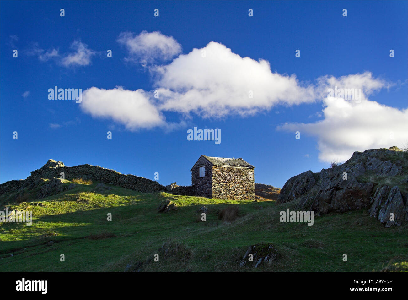 A small slate stone shed stands alone on the Cumbrian fells on a bright ...