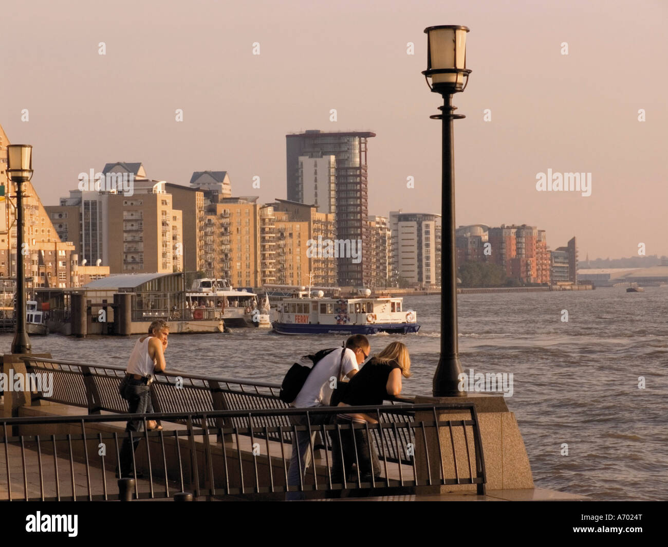 People looking at River Thames with modern riverside flats beyond the ...