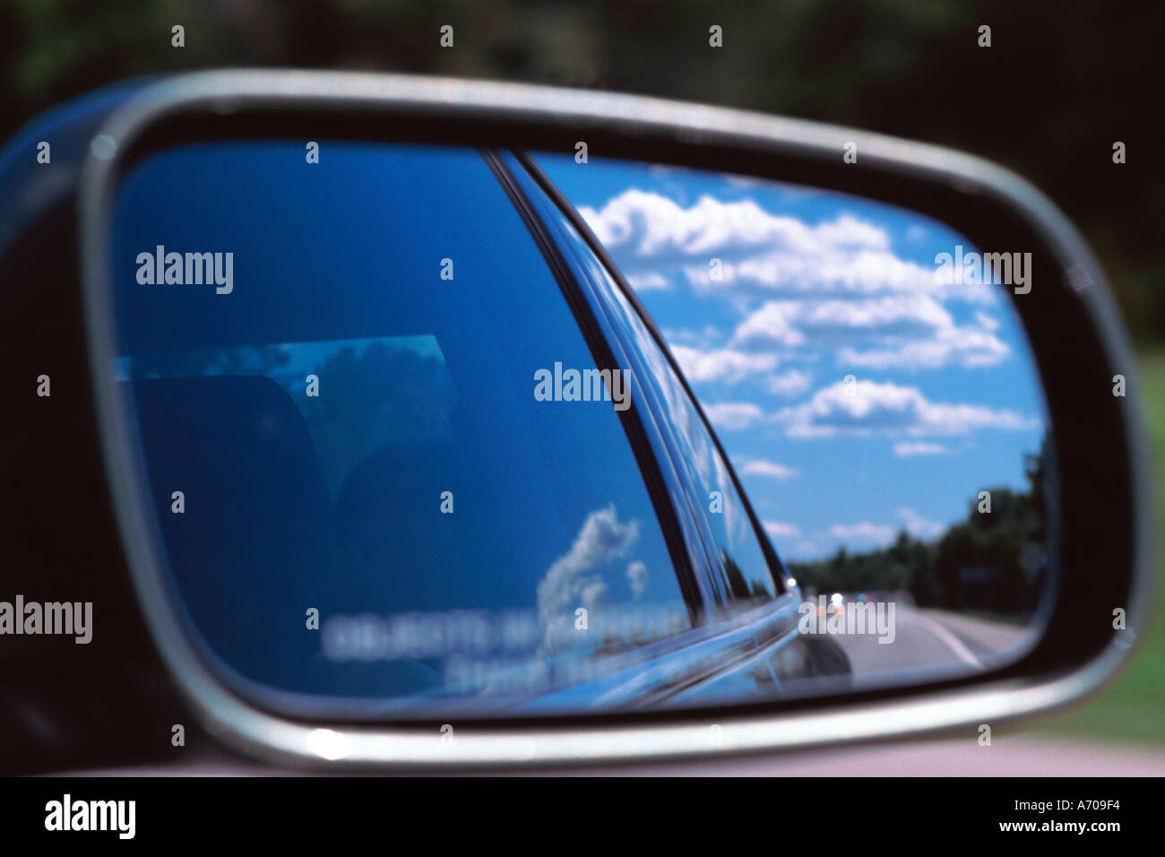 Rearview mirror mounted on auto with road and clouds in scene Stock ...