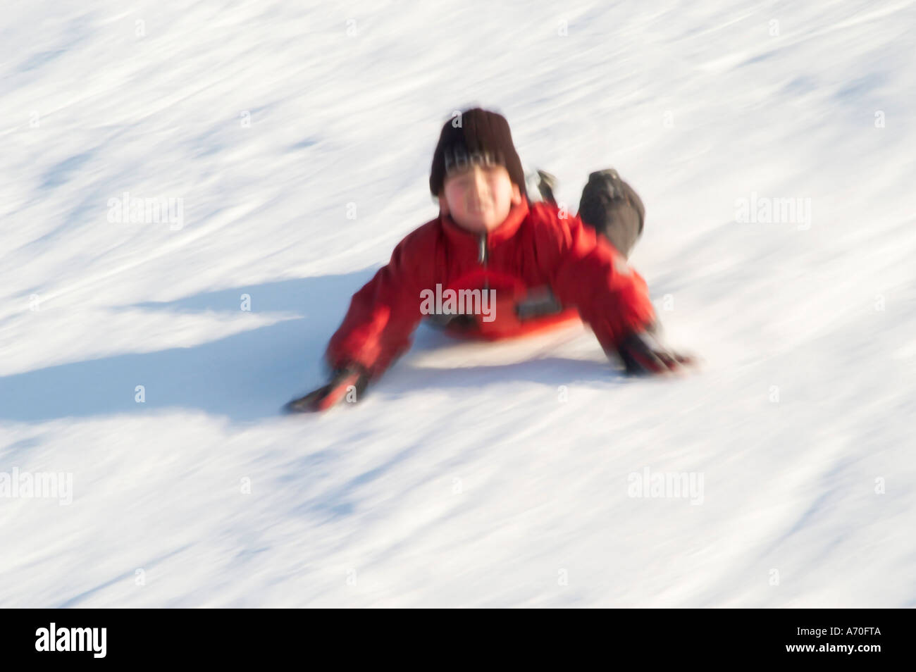 Boy sliding on his belly downhill Stock Photo - Alamy
