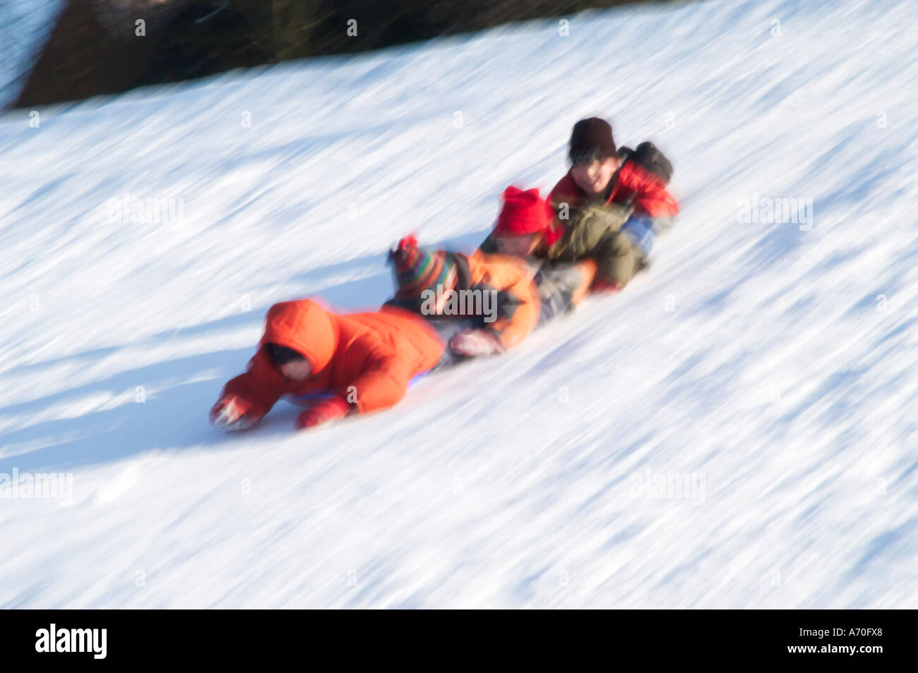Chain of children sliding on their bellies downhill Stock Photo - Alamy