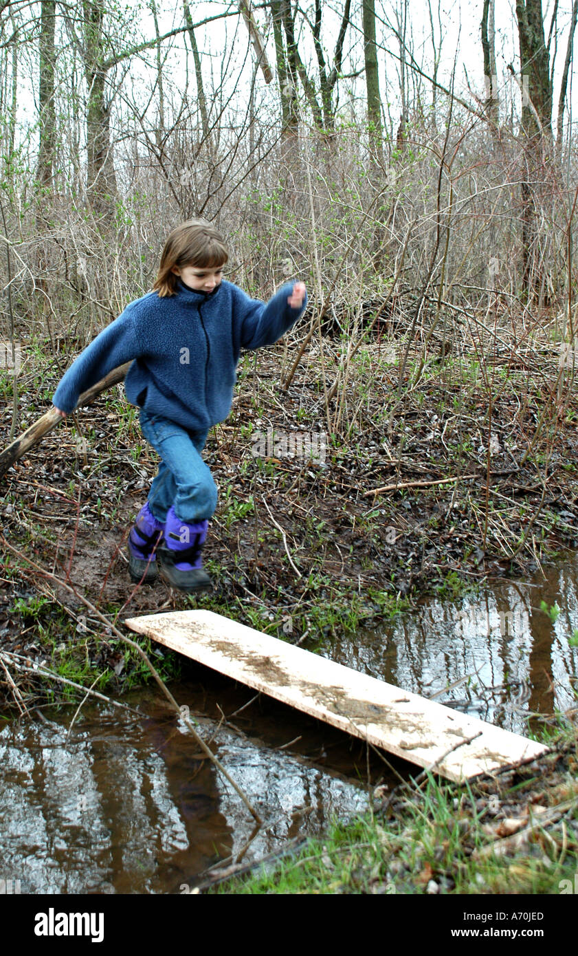 Child jumping onto bridge over stream Stock Photo - Alamy