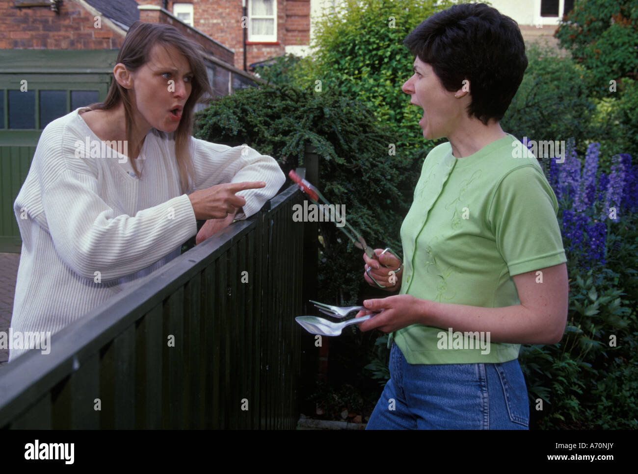 two women fighting over the fence about barbecues Stock Photo - Alamy