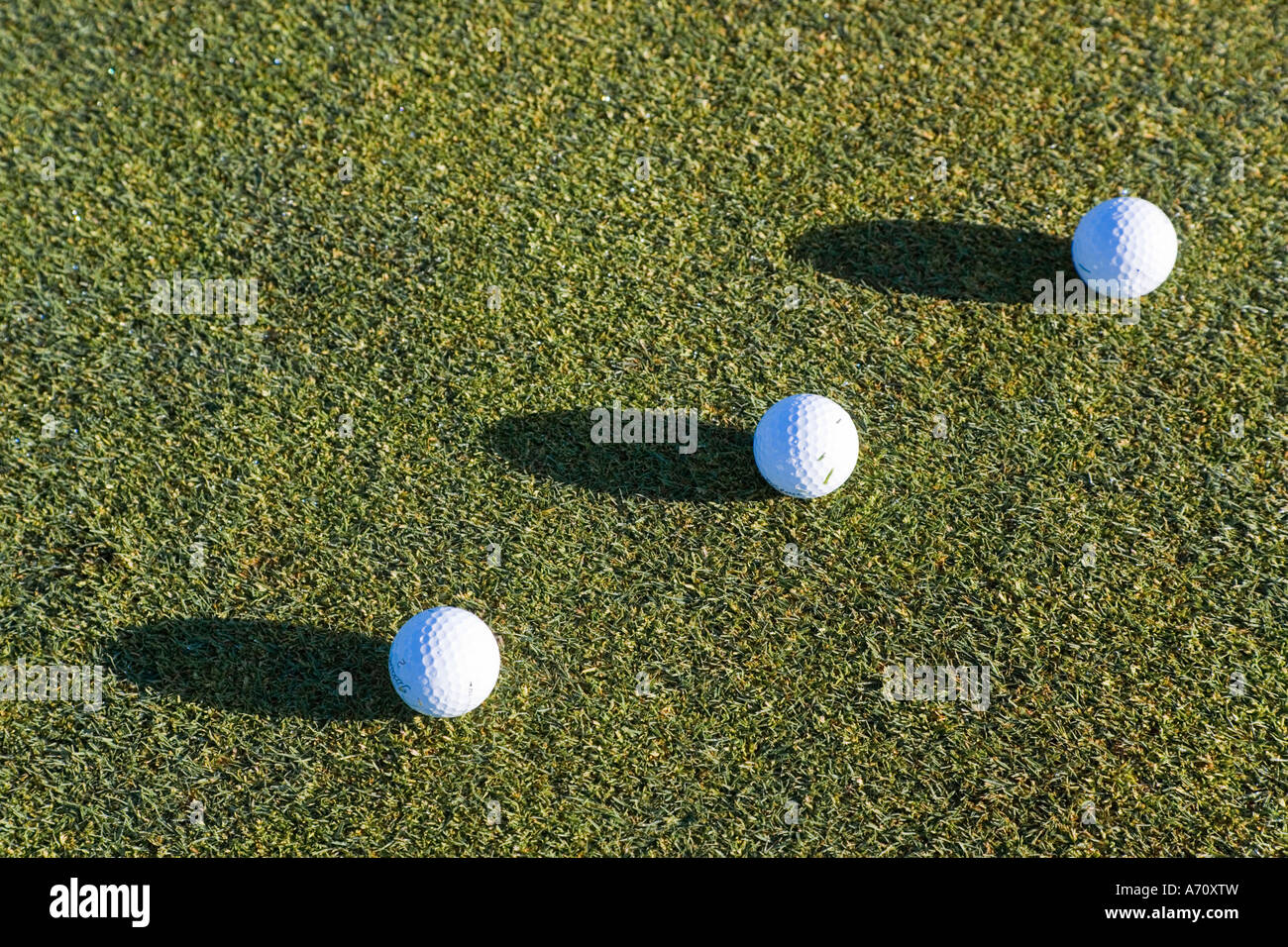 Three golf balls lined up on putting green Stock Photo - Alamy