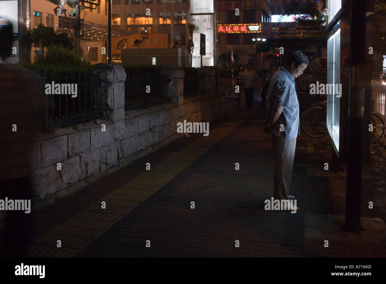 Asia China Beijing Man reads newspaper displayed on signboard at night ...