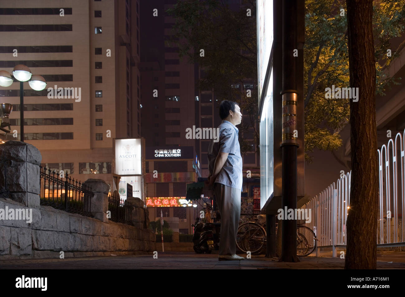 Asia China Beijing Man reads newspaper displayed on signboard at night ...