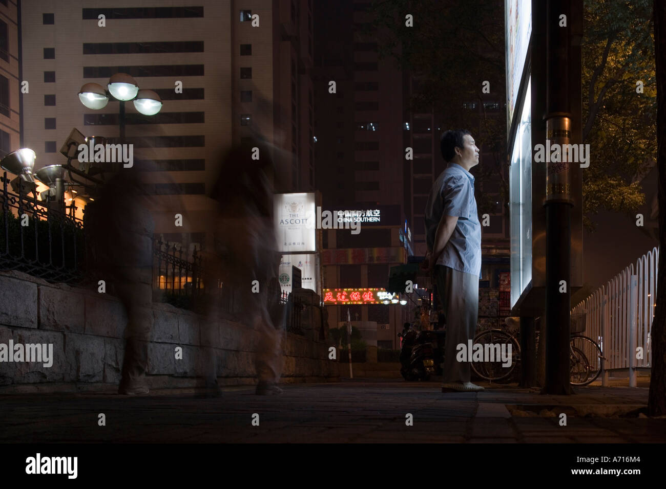 Asia China Beijing Man reads newspaper displayed on signboard at night ...