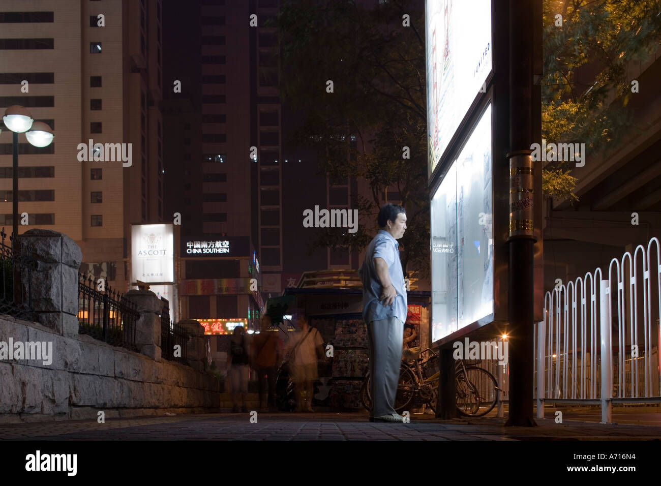 Asia China Beijing Man reads newspaper displayed on signboard at night ...