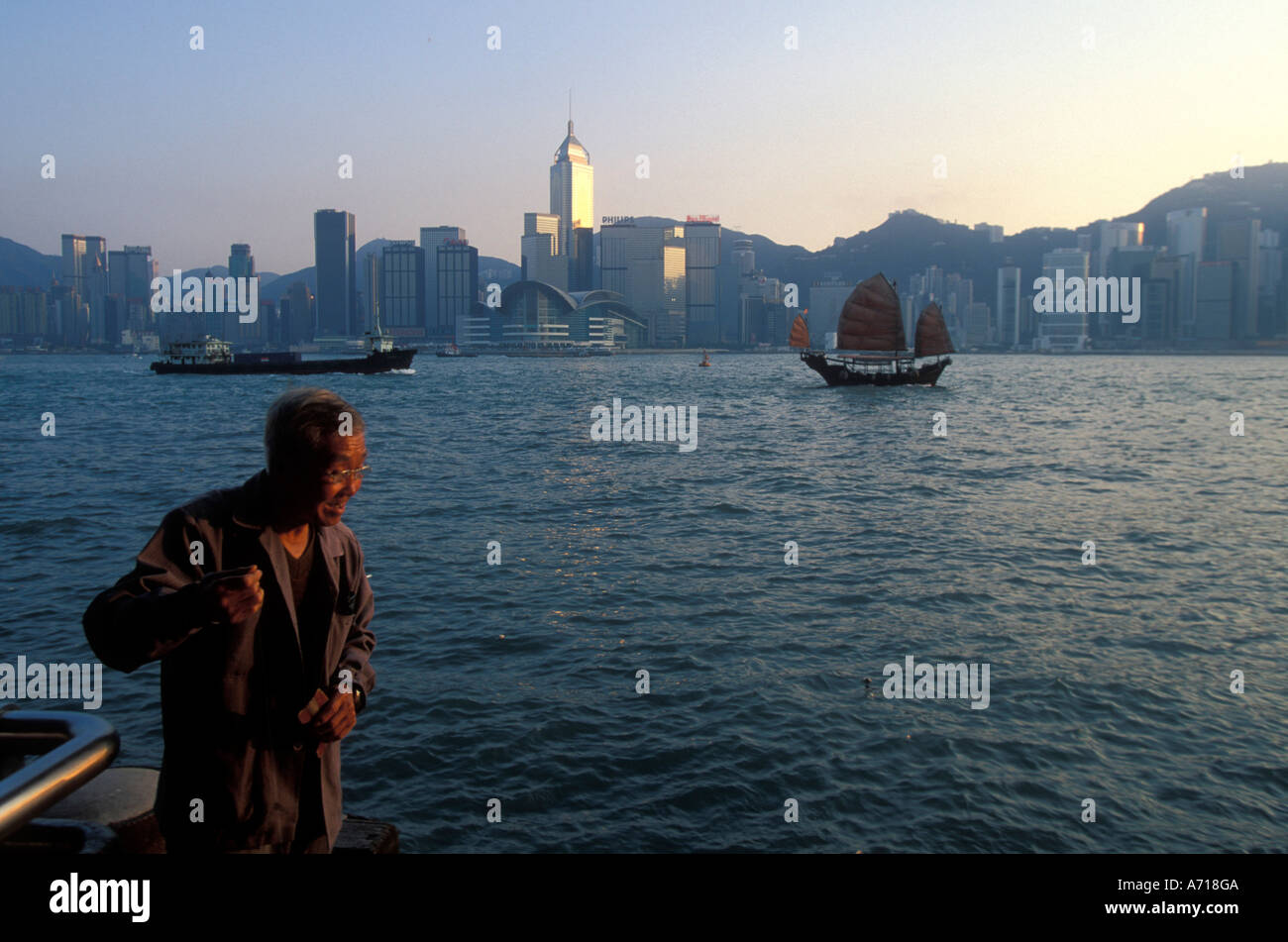 China Hong Kong Man fishes from Kowloon waterfront in Harbour at sunset ...