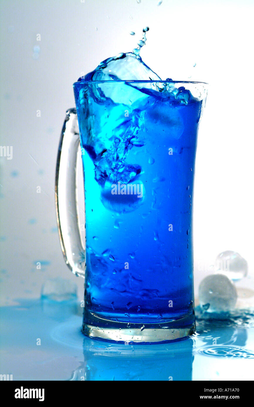 Ice being dropped into glass with blue liquid Stock Photo - Alamy
