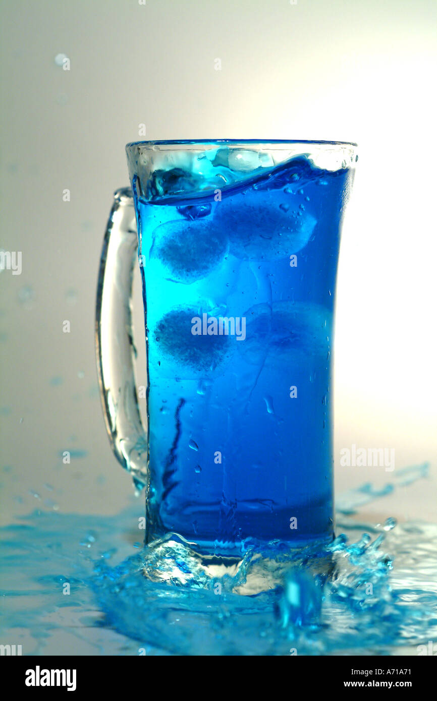 Ice being dropped into glass with blue liquid Stock Photo - Alamy