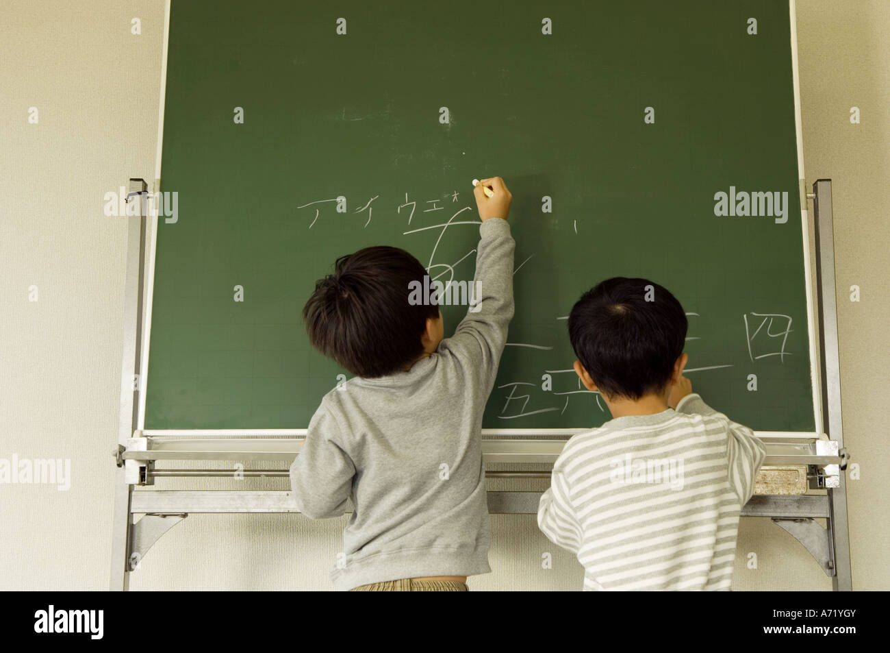 Boys writing on blackboard Stock Photo - Alamy
