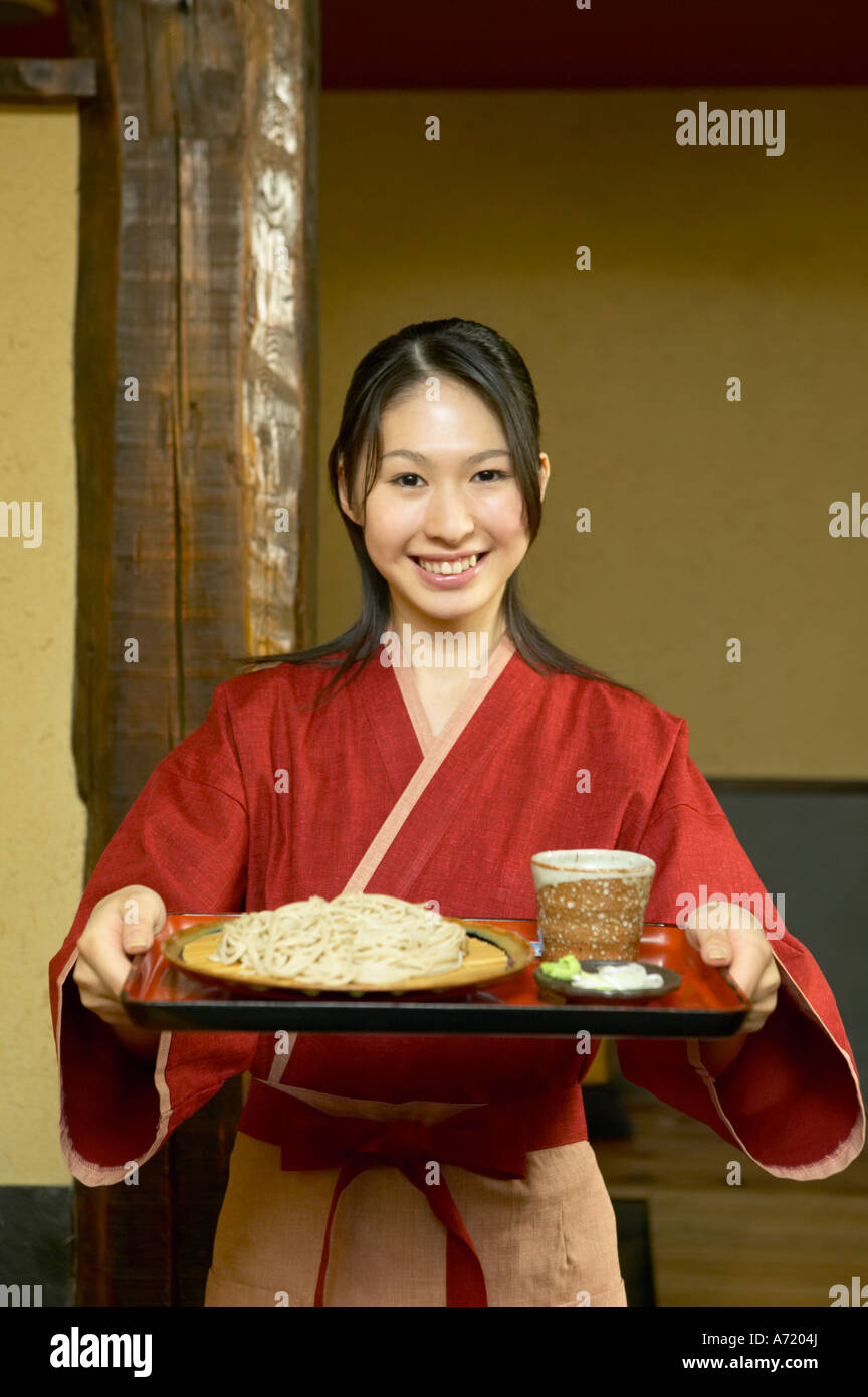 Young woman carrying a tray of noodles Stock Photo - Alamy