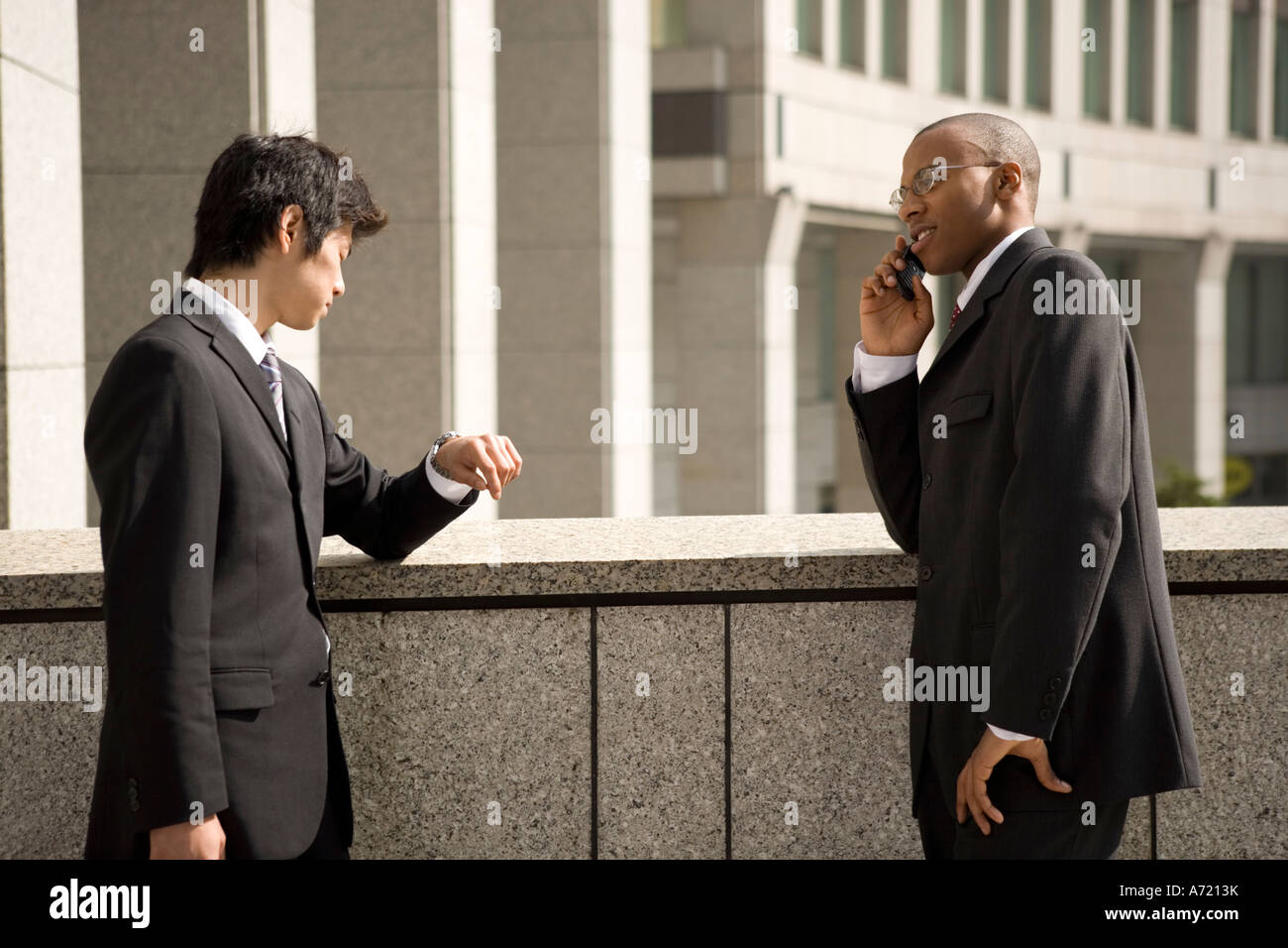Two businessmen, one using mobile phone Stock Photo - Alamy