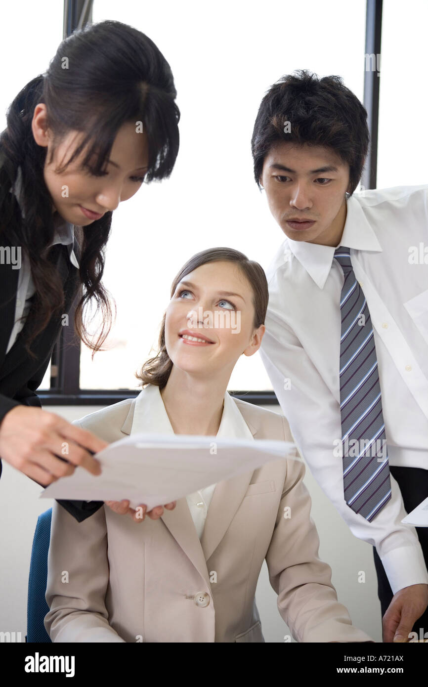Three business people looking at documents Stock Photo - Alamy