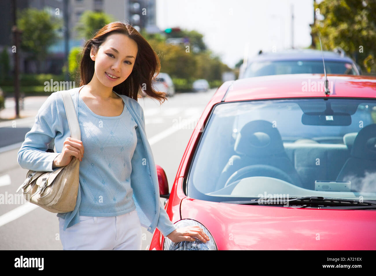 Young woman standing beside car Stock Photo - Alamy