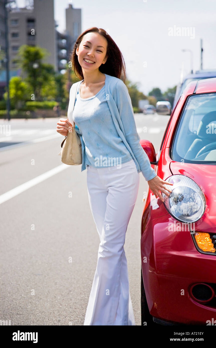 Young woman standing beside car Stock Photo - Alamy