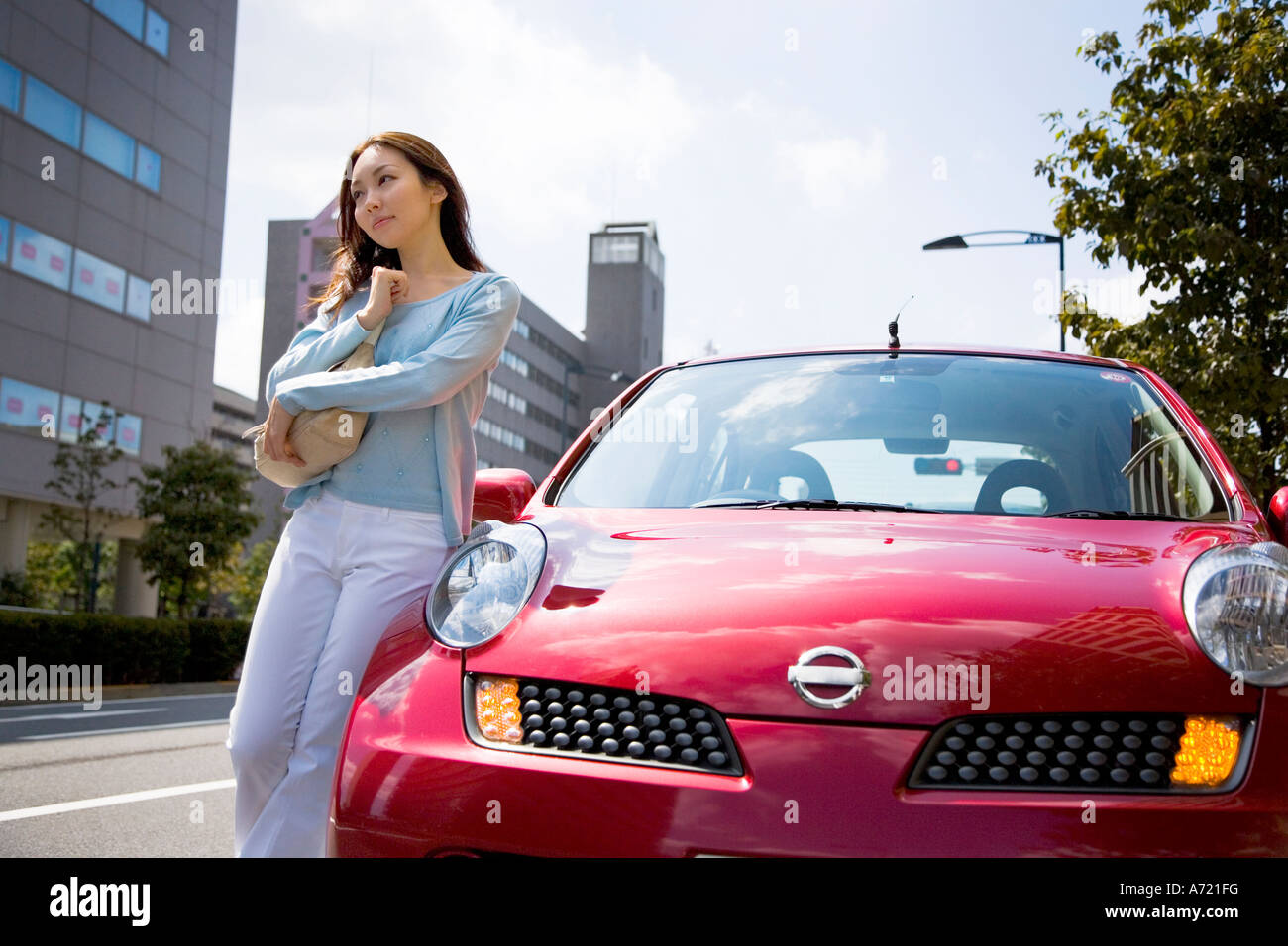 Young woman standing beside car Stock Photo - Alamy