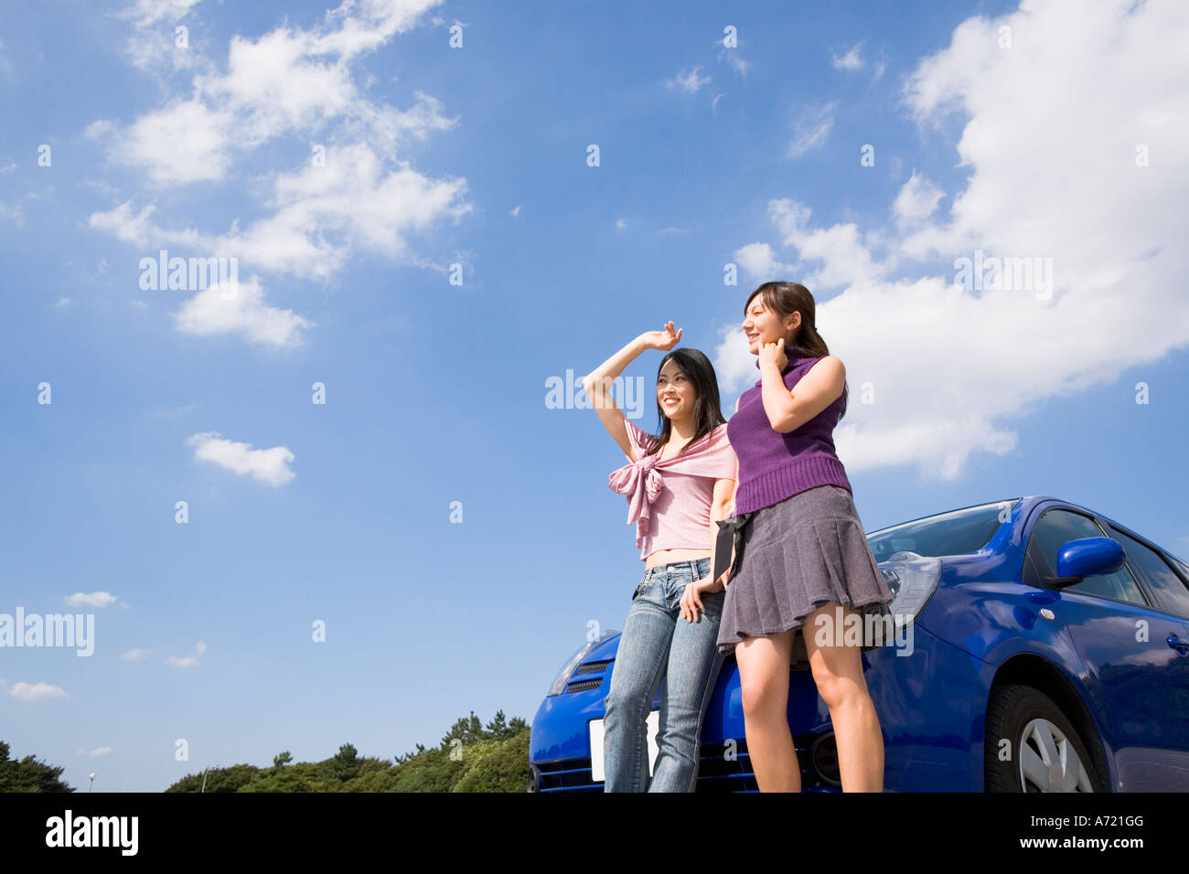 Two young women standing beside car Stock Photo - Alamy