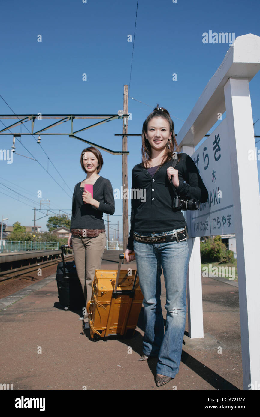 Two young women standing on train platform Stock Photo - Alamy