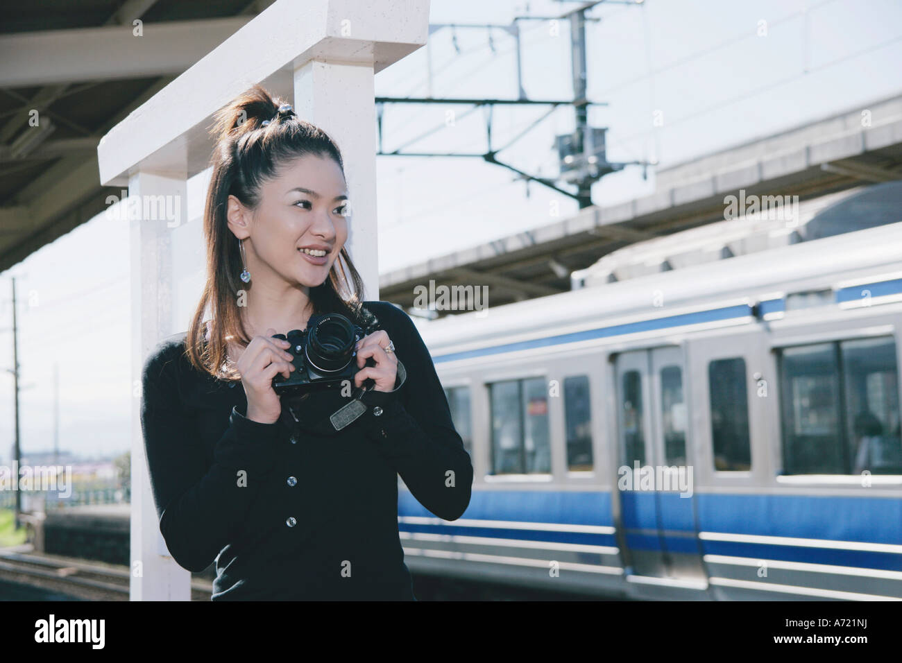 Young woman taking photograph on train platform Stock Photo - Alamy