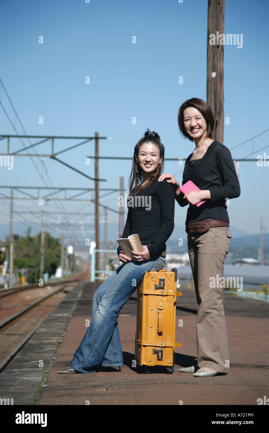 Two young women standing on train platform Stock Photo - Alamy
