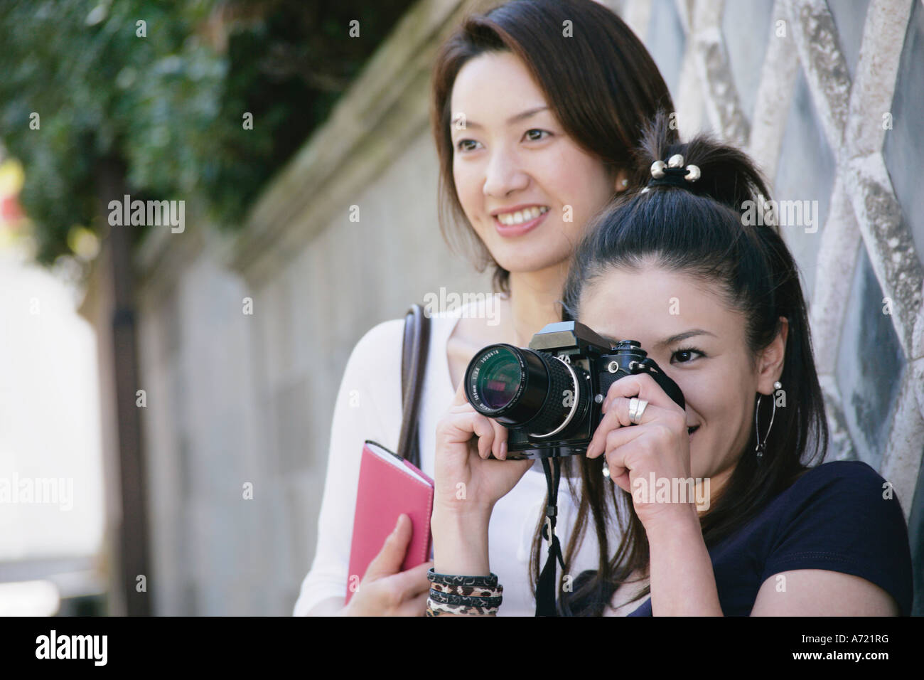 Two young women, one taking photograph Stock Photo - Alamy