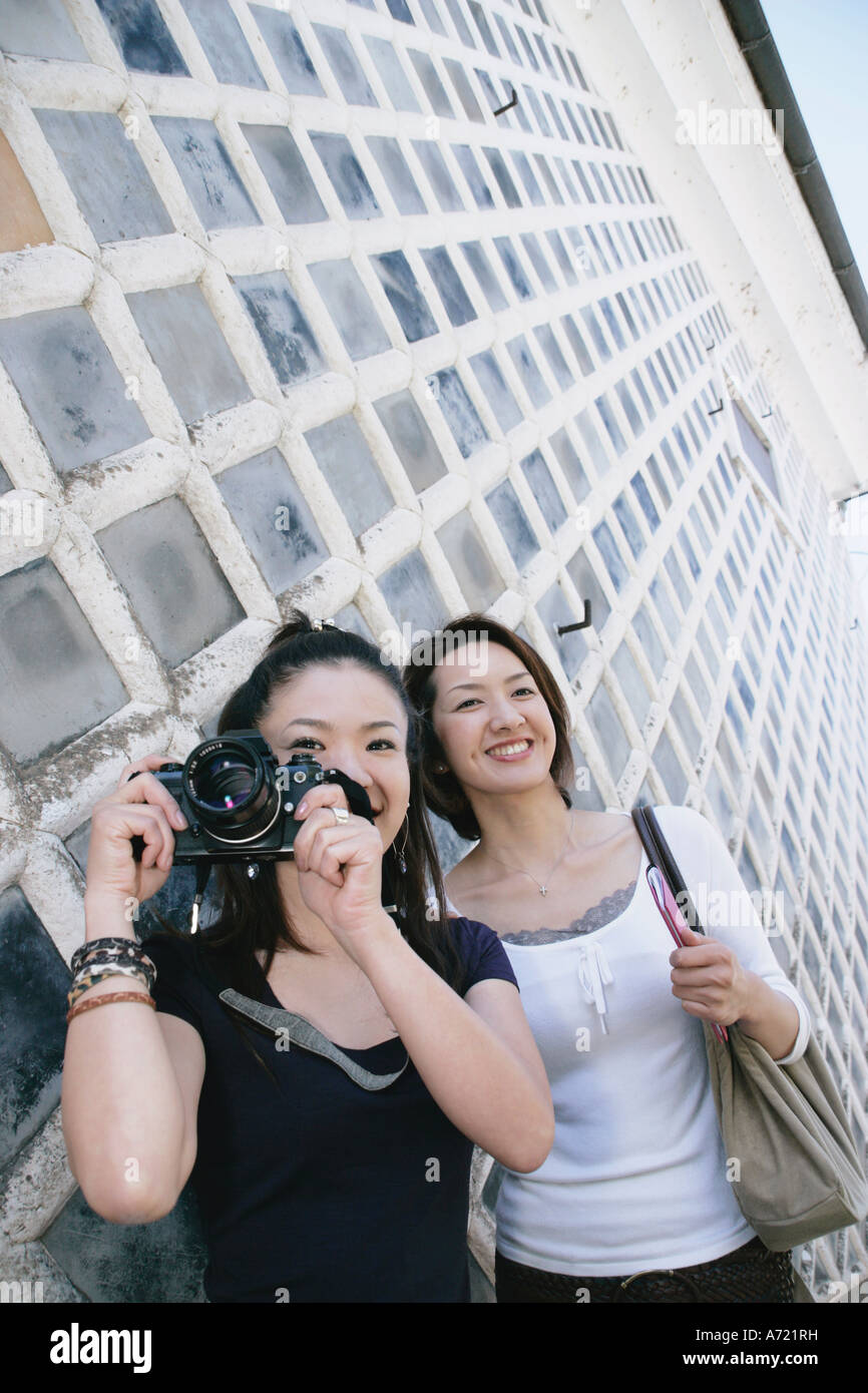 Two young women, one taking photograph Stock Photo - Alamy