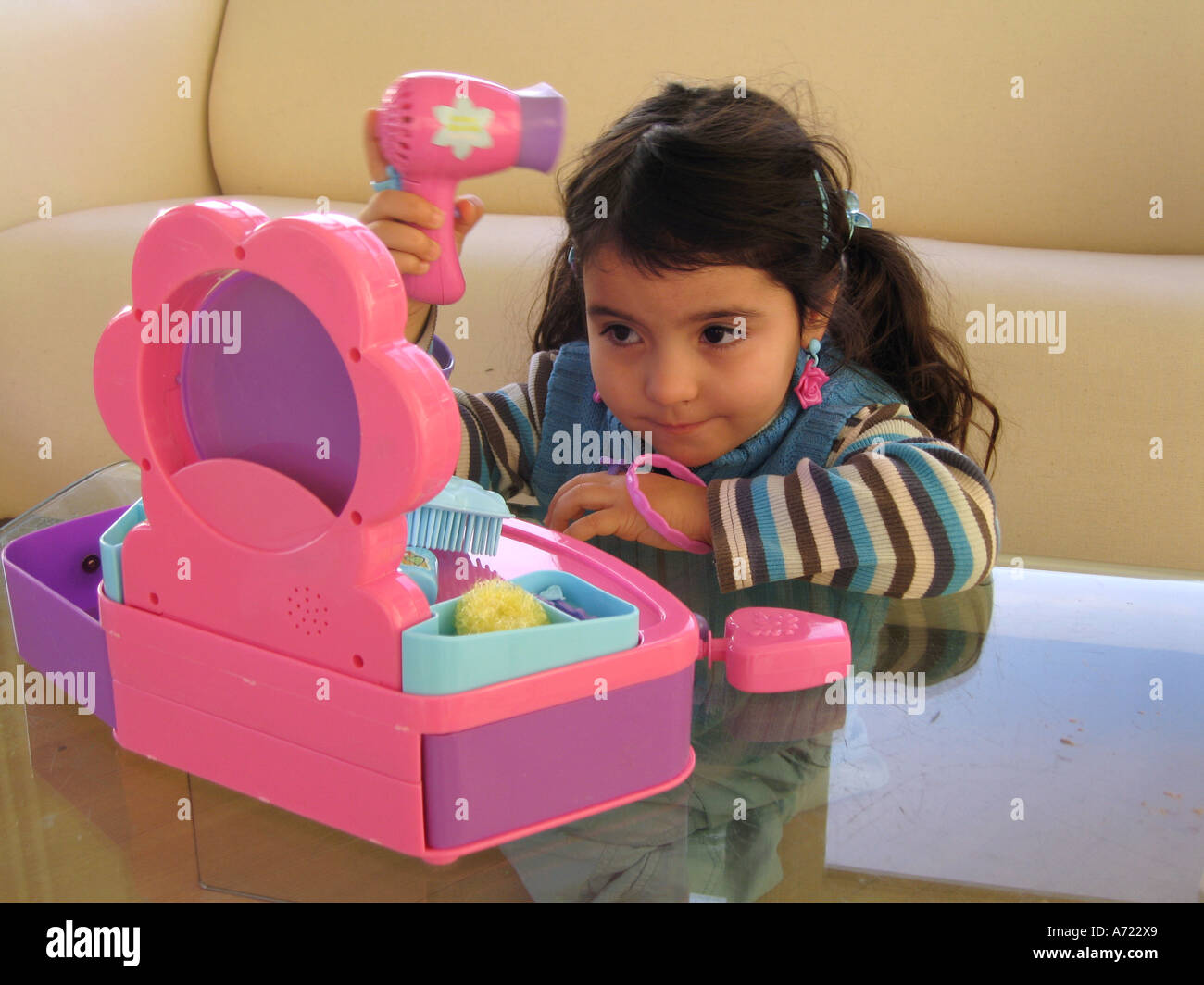 Little girl is playing with make up and toy fohn Stock Photo - Alamy